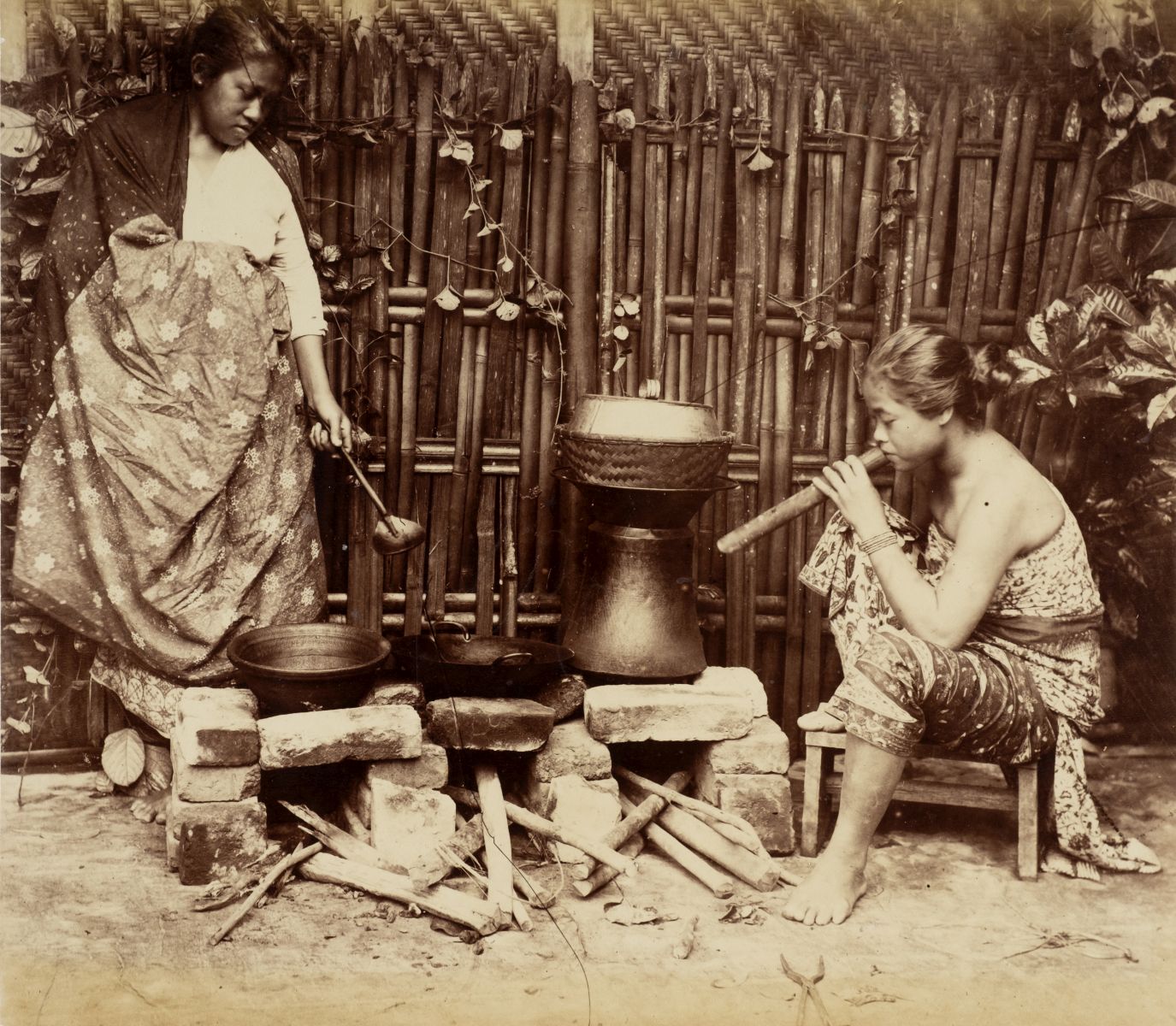 Lot 67 - Indonesia. Two Malay women cooking on bricks